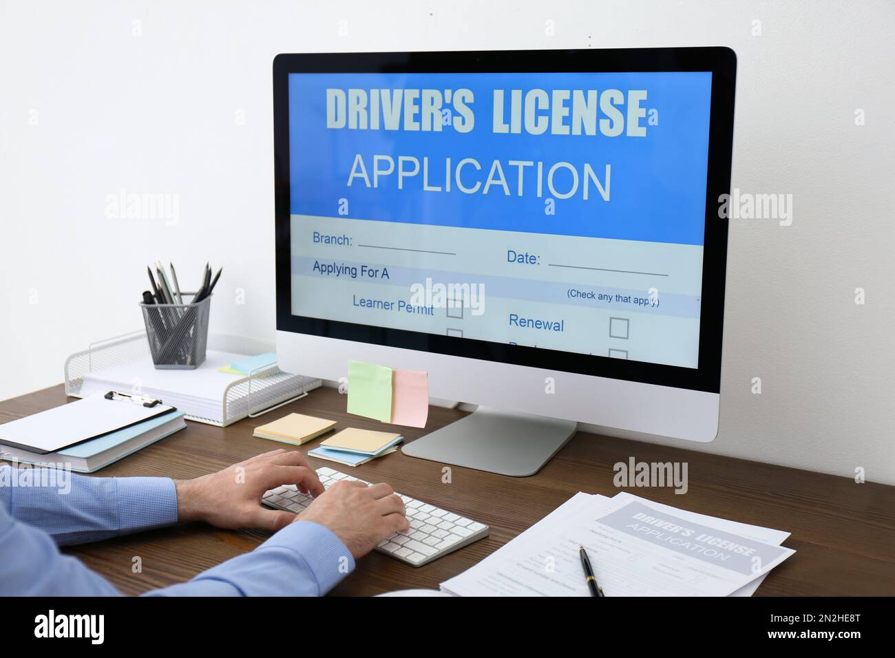Man using computer to fill driver's license application form at table in office, closeup Stock ...
