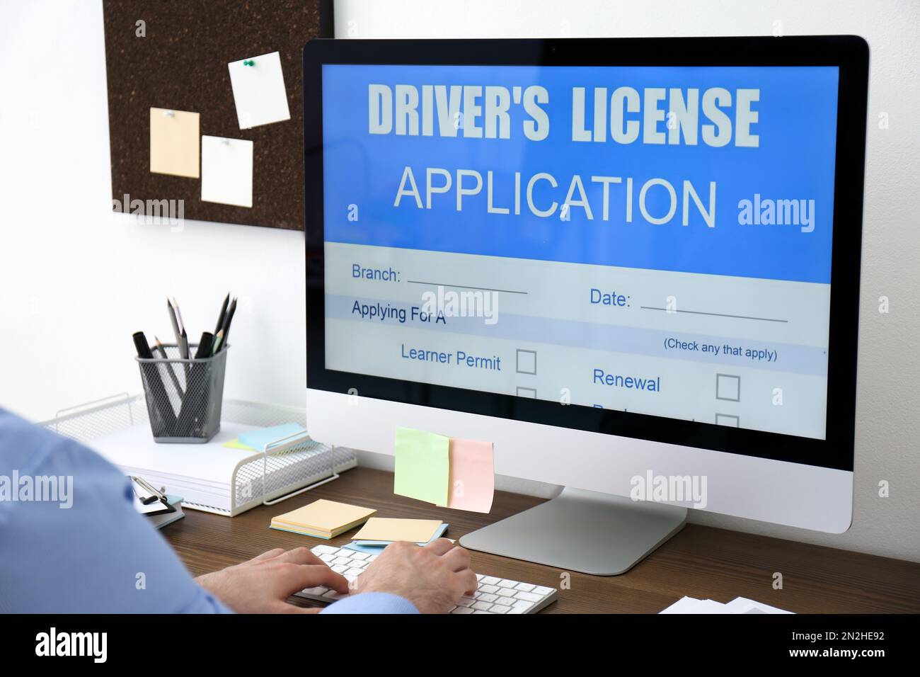 Man using computer to fill driver's license application form at table in office, closeup Stock ...