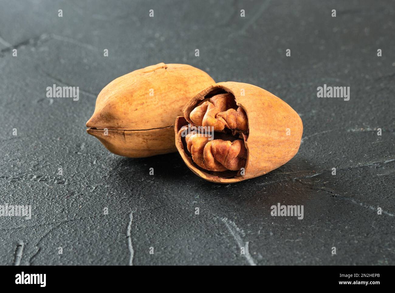 Inshell pecan with split half on dark concrete background Stock Photo ...