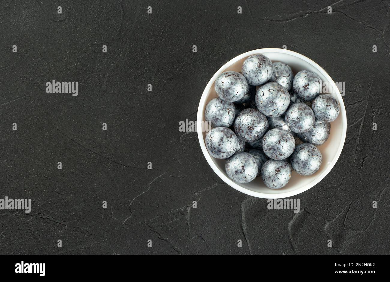 Silver candies hazelnuts in chocolate in a white ceramic bowl on a ...