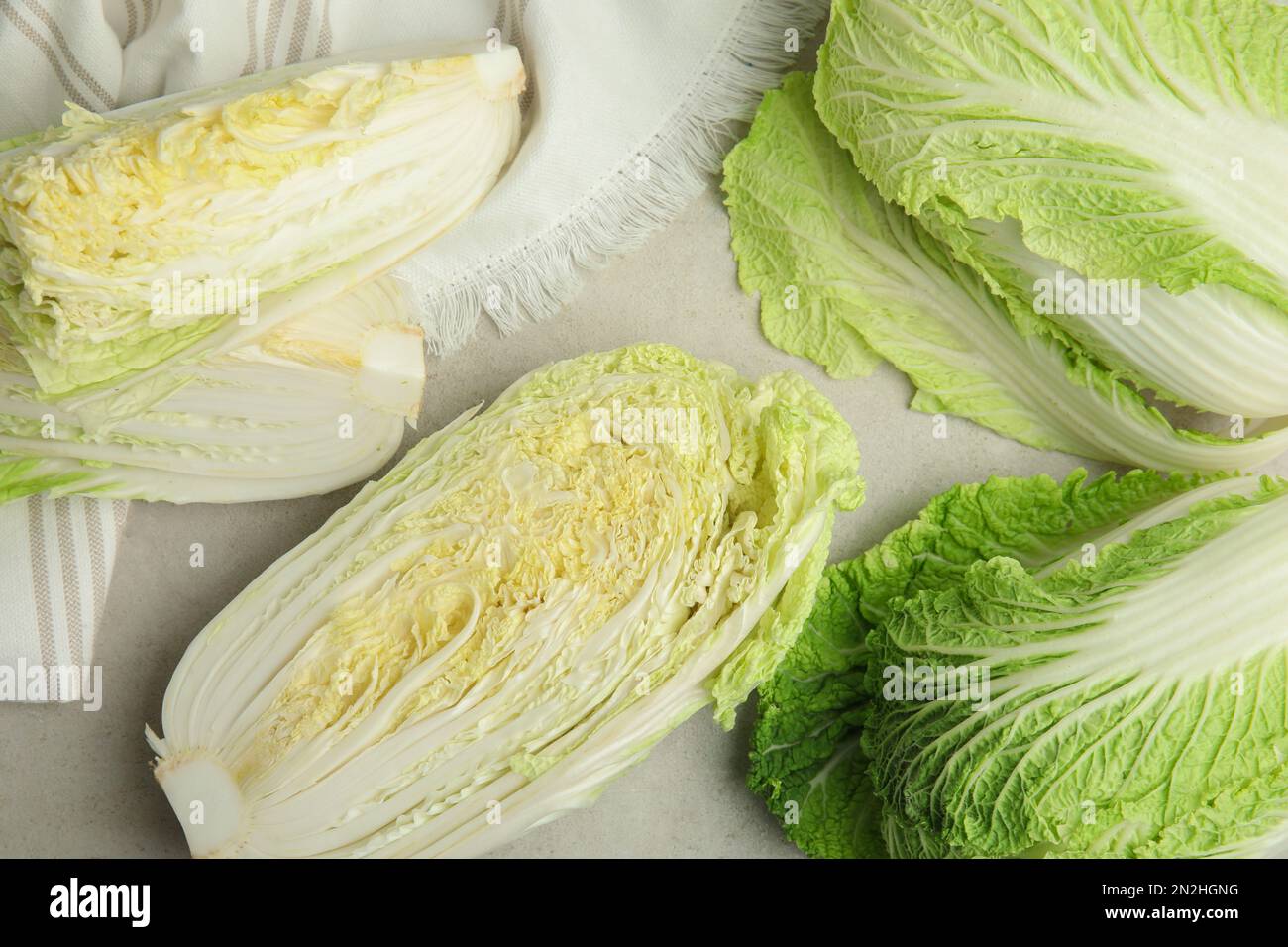 Whole and cut fresh Chinese cabbages on light grey table, flat lay ...