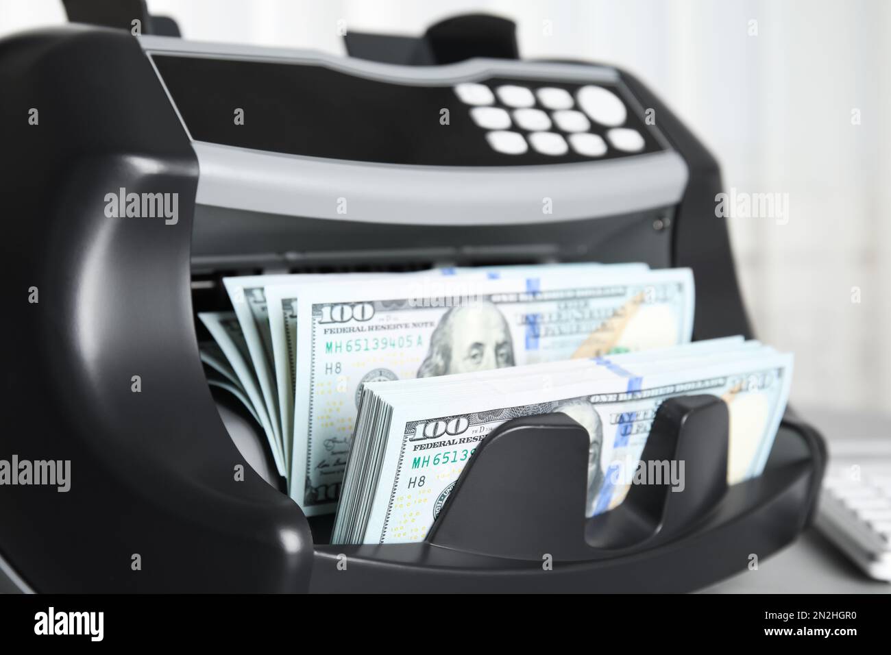 Modern electronic bill counter with money on table indoors, closeup ...