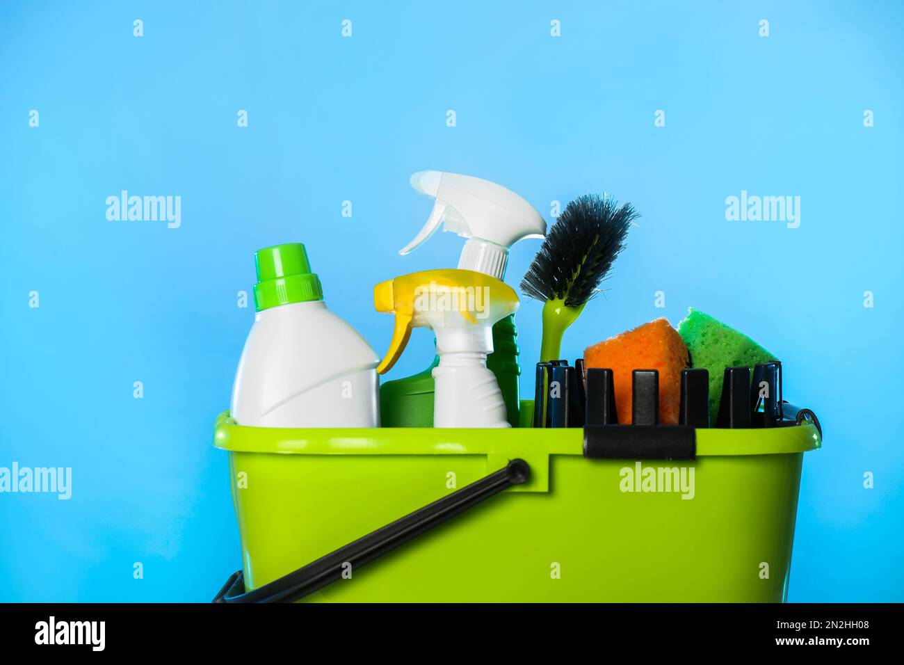 Bucket with different cleaning products and supplies on light blue ...