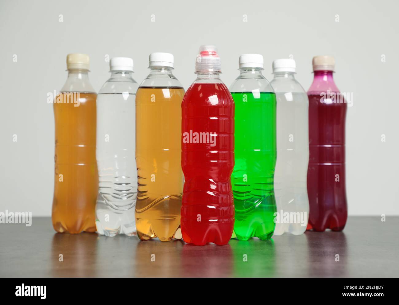 Bottles of soft drinks on table against grey background Stock Photo - Alamy