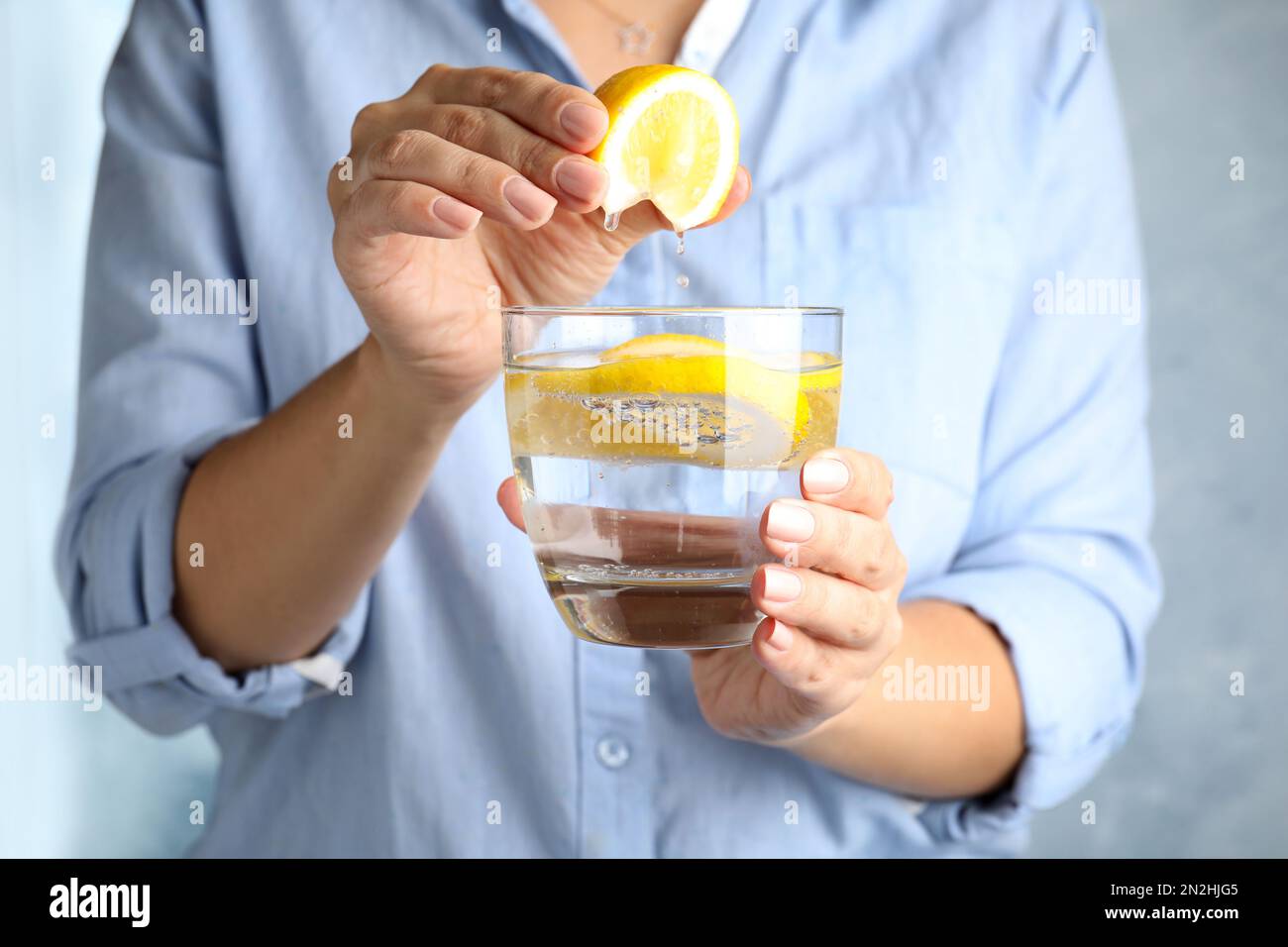 Woman squeezing lemon juice into glass of soda water, closeup Stock Photo - Alamy