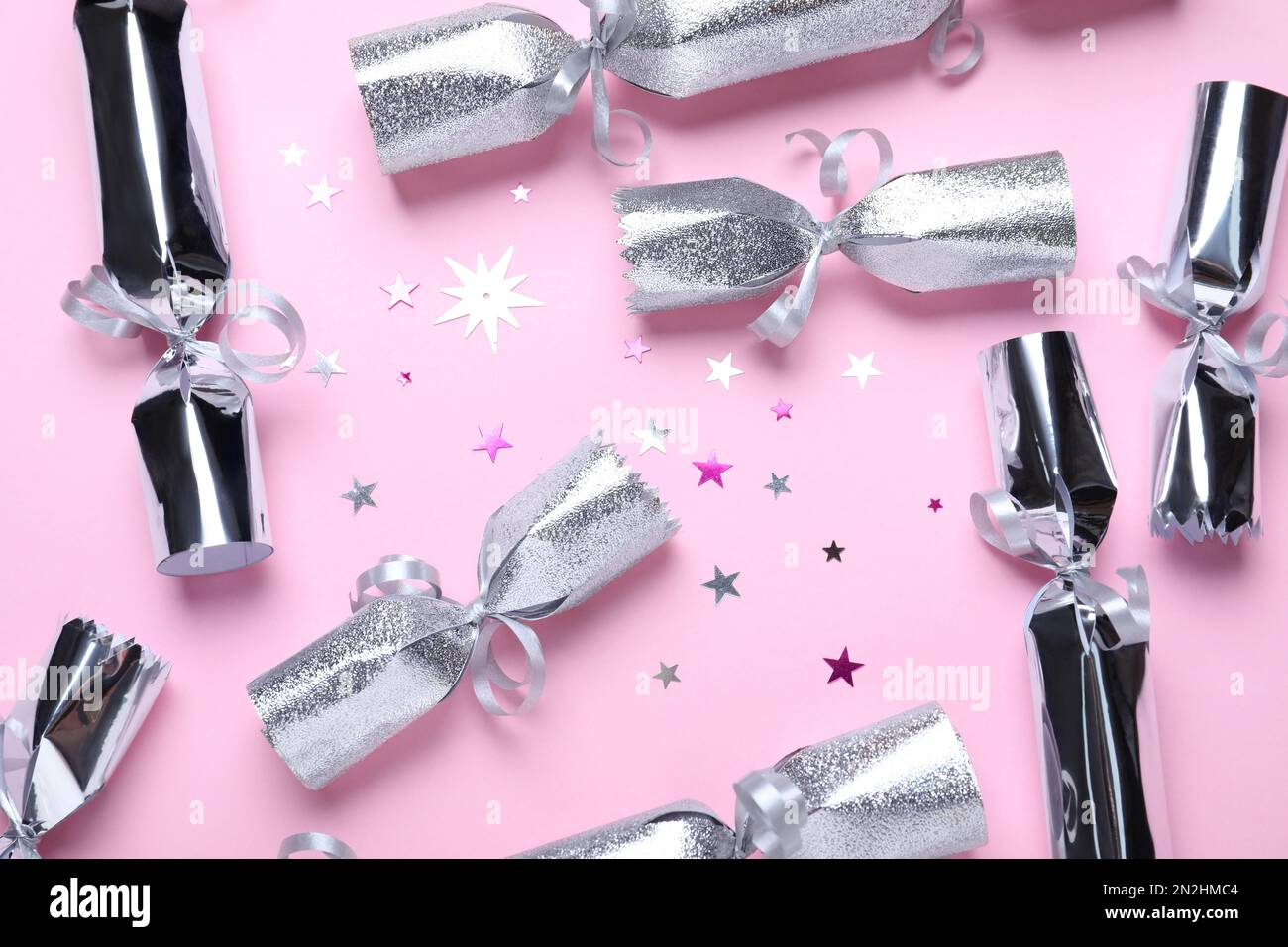Open and closed silver Christmas crackers with shiny confetti on pink ...