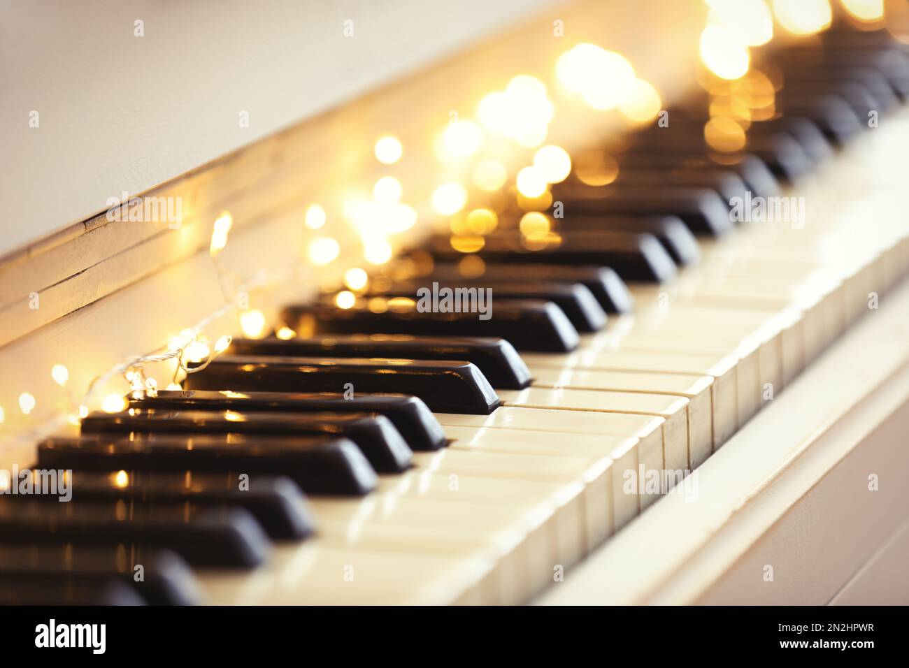 Glowing fairy lights on piano keys, closeup. Christmas music Stock ...