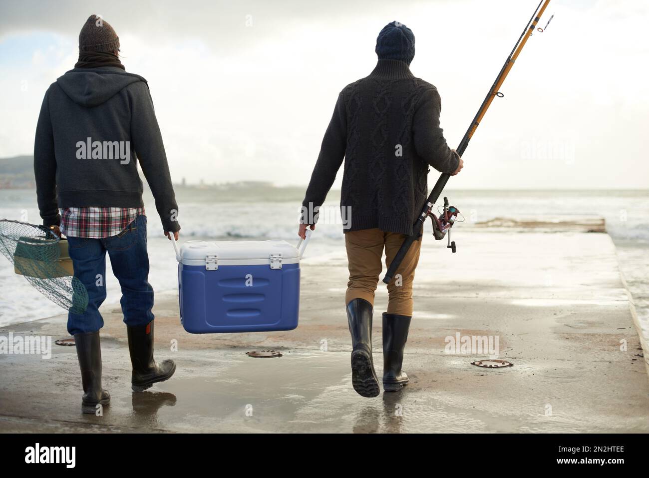 Carrying todays haul. two young men fishing at the ocean in the early ...