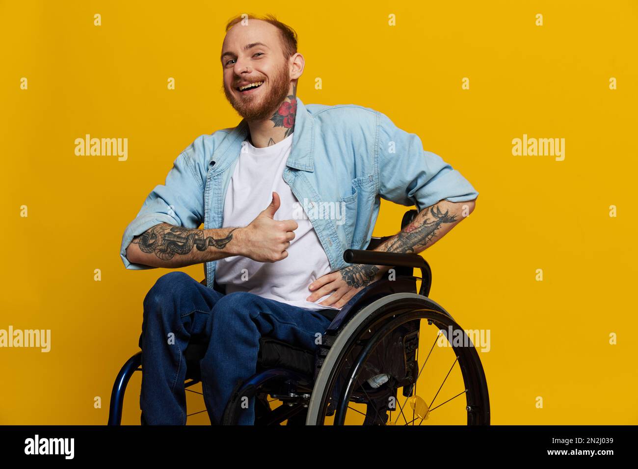 A man in a wheelchair smile and happiness, thumb up, with tattoos on ...
