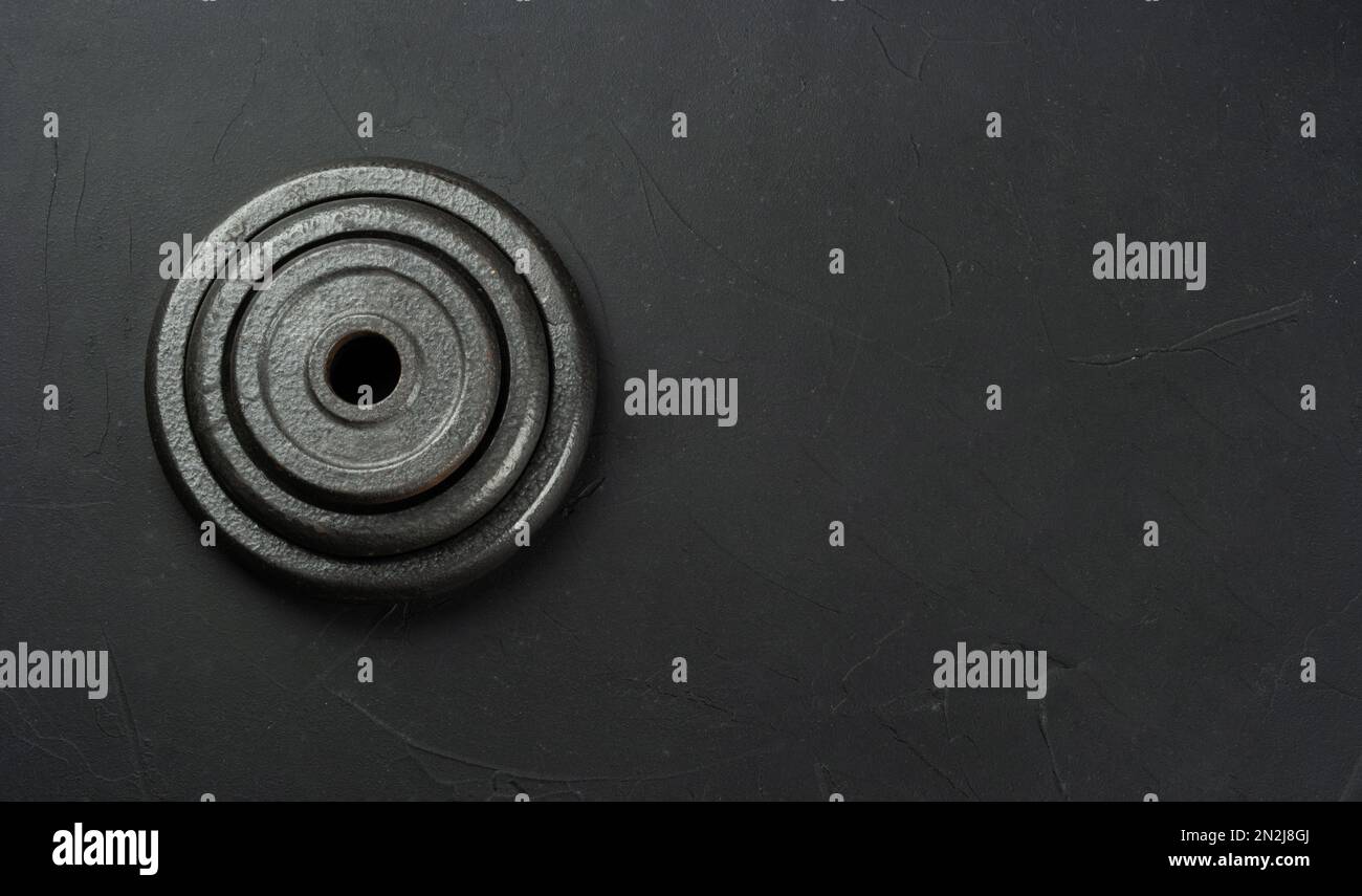 Metal pancakes from dumbbells in a heap on an empty dark background ...