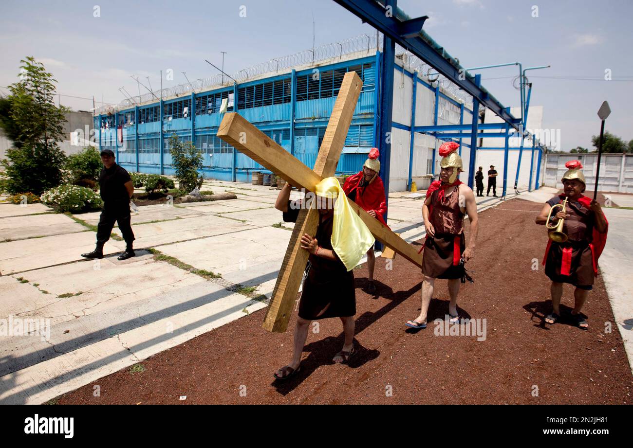 An inmate carries a cross while others play the role of Roman soldiers ...