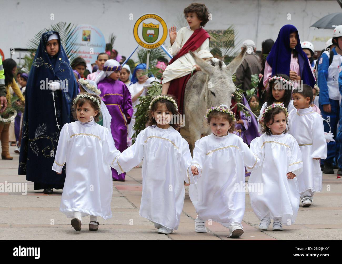 Children dressed as angels lead a boy portraying Jesus Christ and his ...