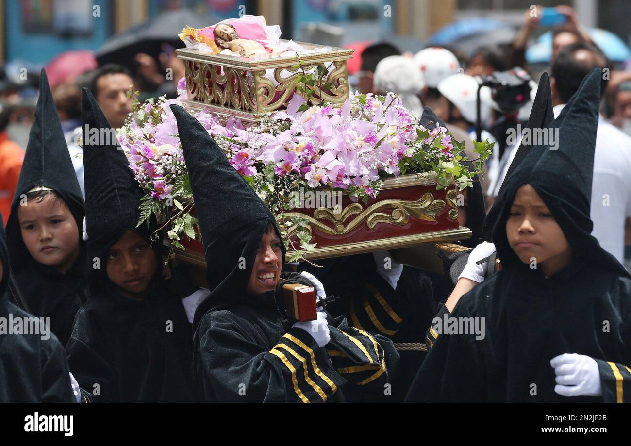 Young boys dressed as penitents carry the religious float representing ...