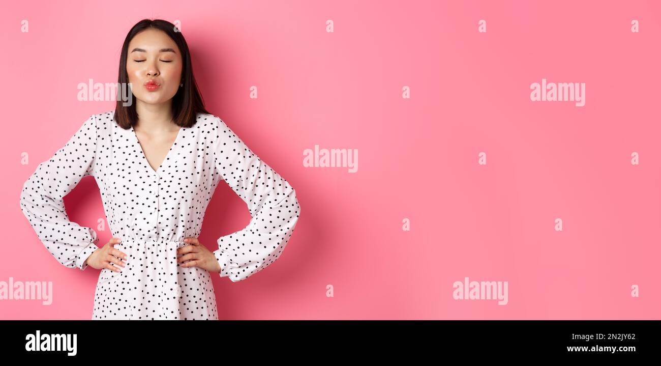 Beautiful asian woman in dress pucker lips and close eyes, waiting for ...
