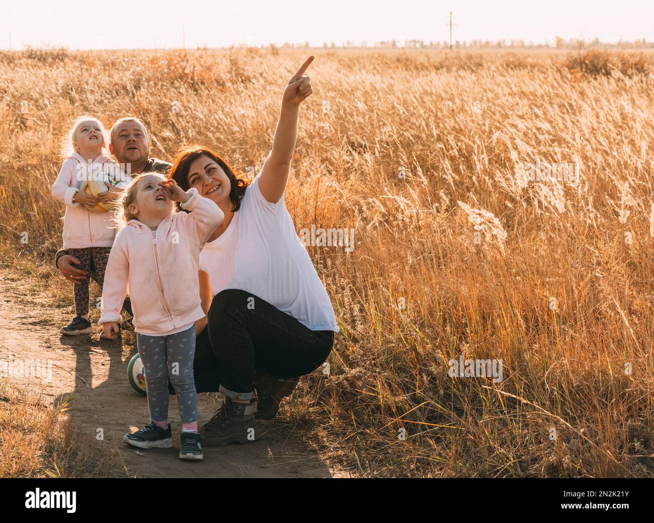 young happy family rests outdoors and indicates something interesting ...