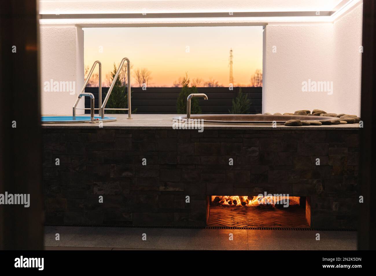 Modern big hot tub outdoor in sunset. Bonfire under tube warming water ...