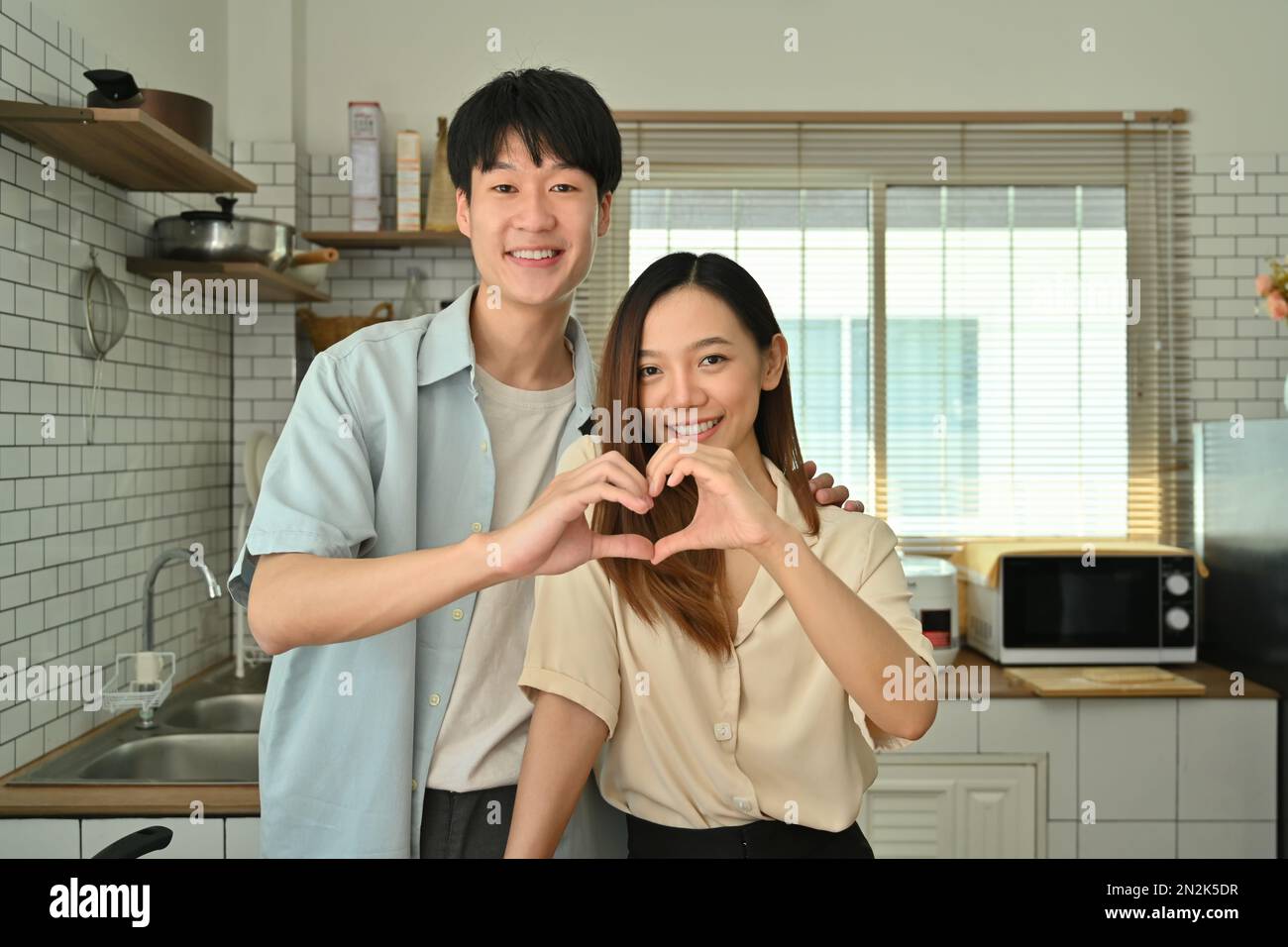 Portrait of beautiful young married couple making heart shape with ...