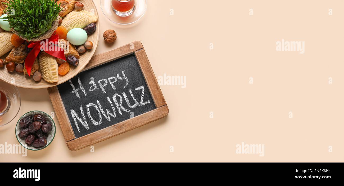 Chalkboard with text HAPPY NOWRUZ, sweets and green wheat grass on ...