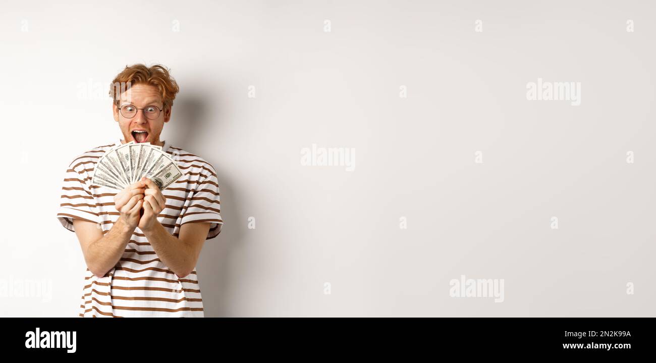 Lucky young man with red hair showing dollars, winning money and ...