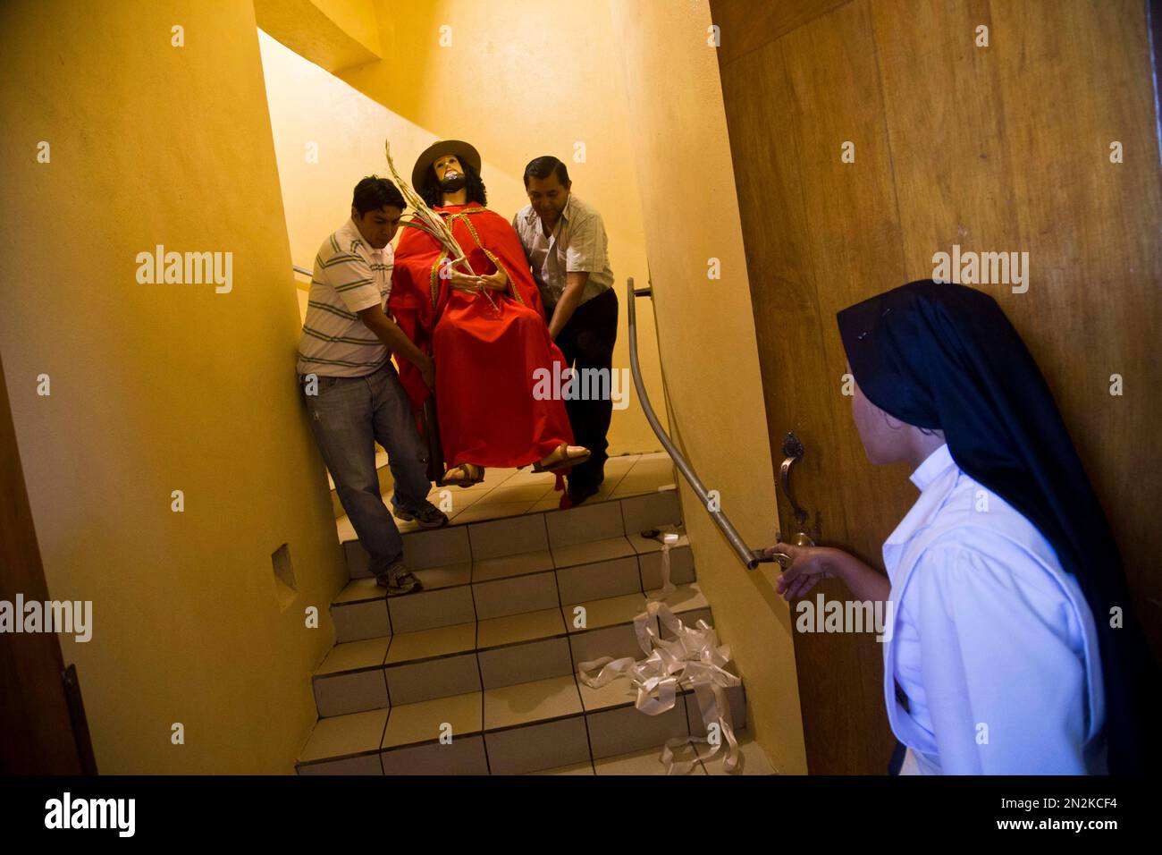 Church volunteers carry a statue of Jesus to a waiting donkey outside ...