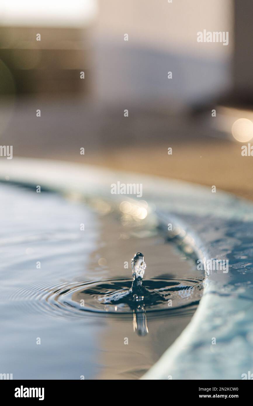 Macro photo of drops of water drip into a clear pool with blue water ...