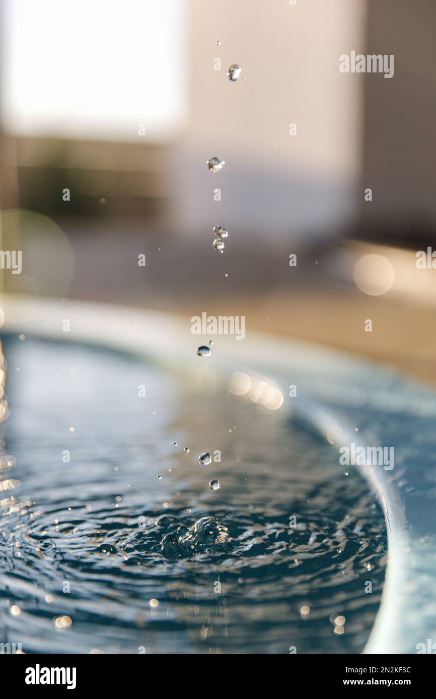 Macro photo of drops of water drip into a clear pool with blue water ...