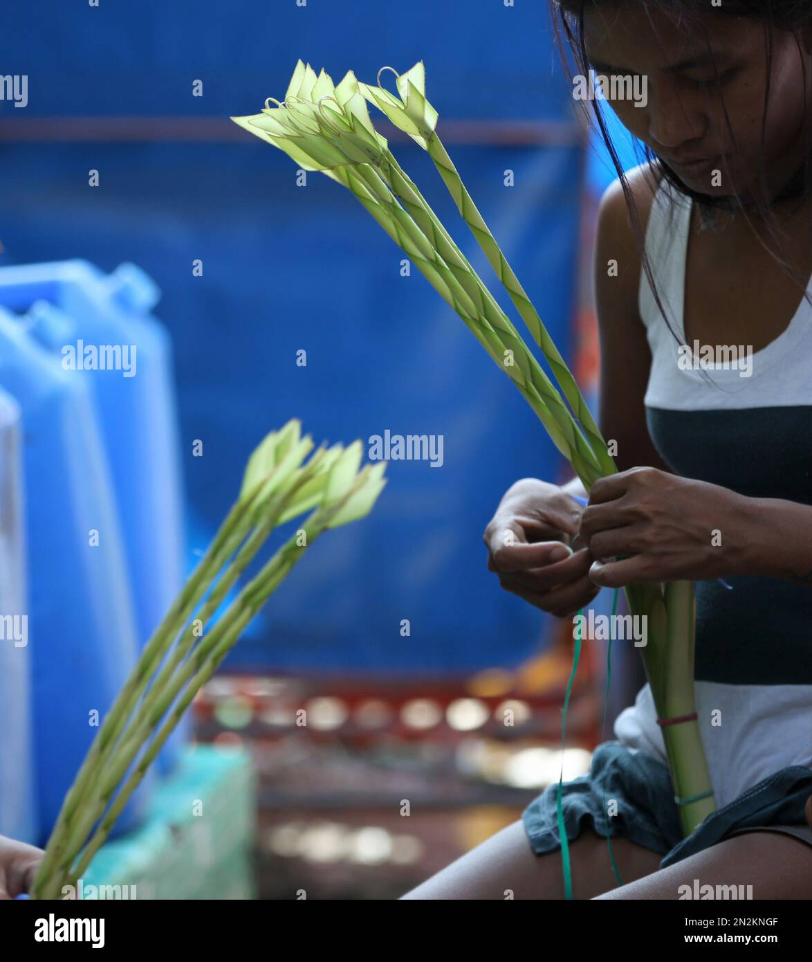 A resident crafts palm fronds to be blessed for Palm Sunday rites among ...