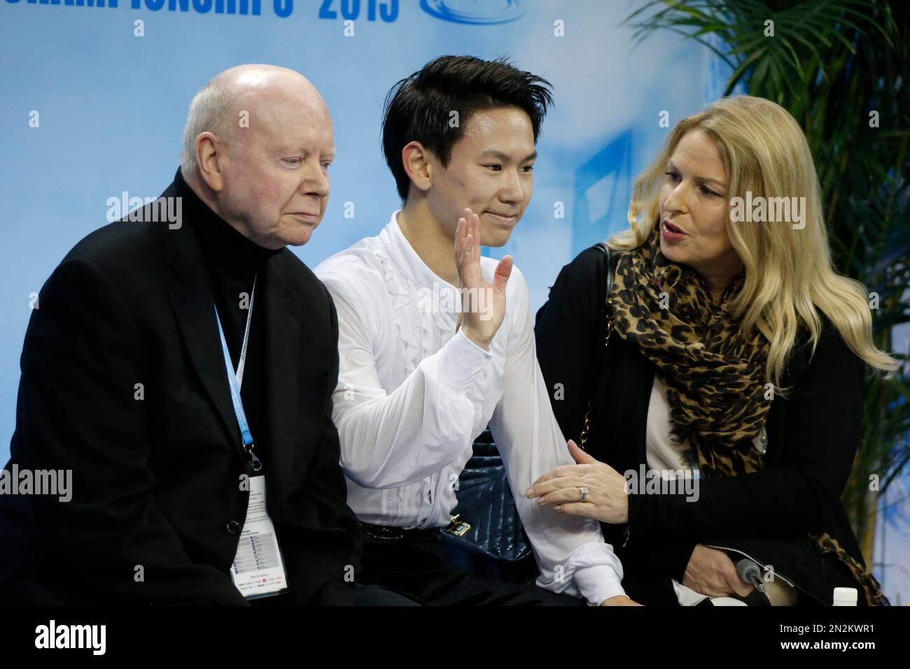 Denis Ten of Kazakstan sits with his coaches after performing in the ...