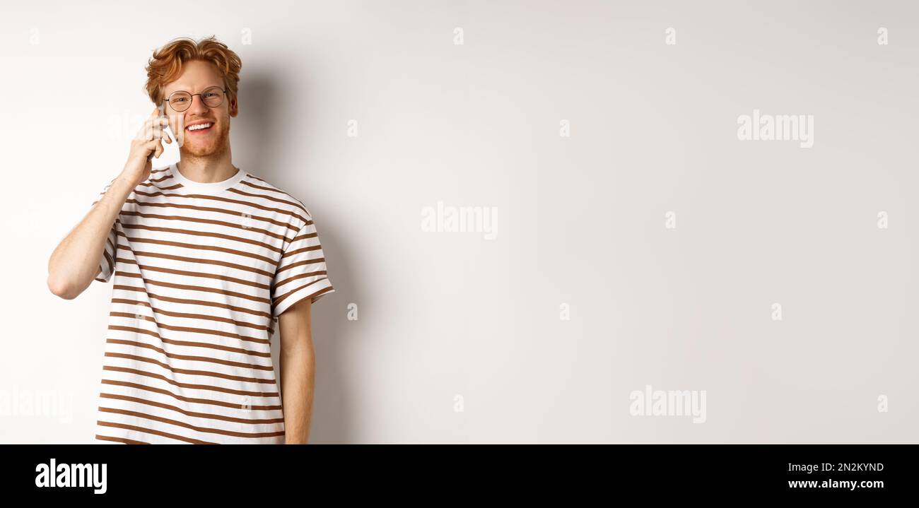 Hipster with red hair and glasses talking on mobile phone, smiling ...