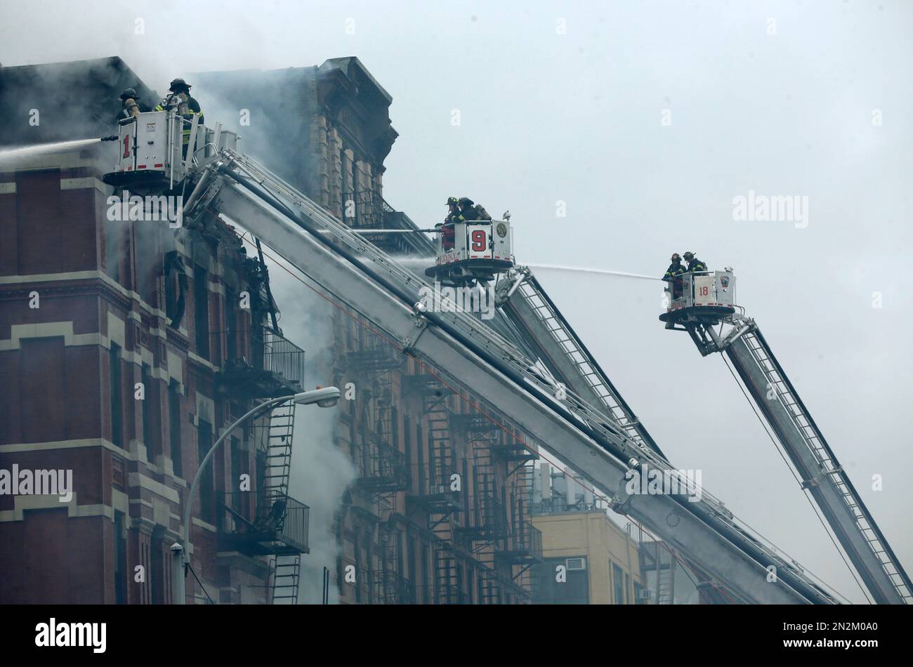 New York City firefighters spray water at the scene of a fire and a ...