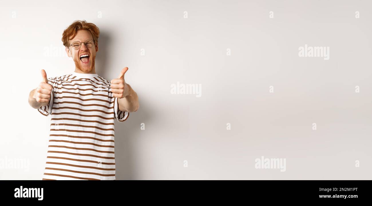 Happy redhead man scream yes and showing thumbs-up, approve and praise ...