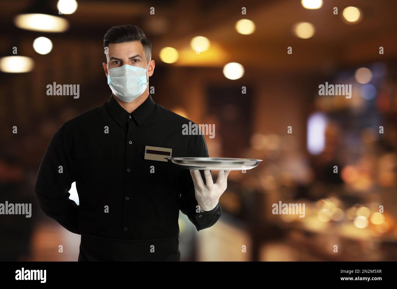 Waiter in medical face mask holding tray in restaurant Stock Photo - Alamy