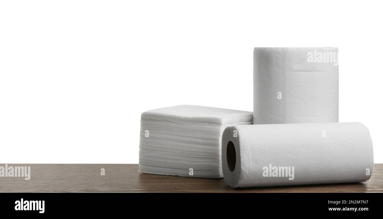Rolls and stack of clean paper tissues on wooden table against white ...