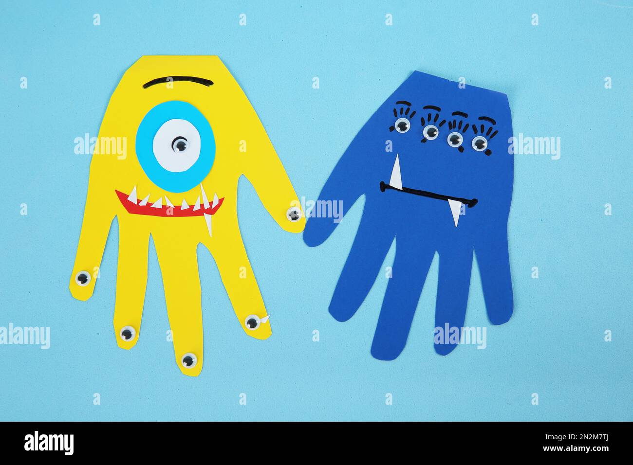 Funny hand shaped monsters on light blue background, flat lay ...