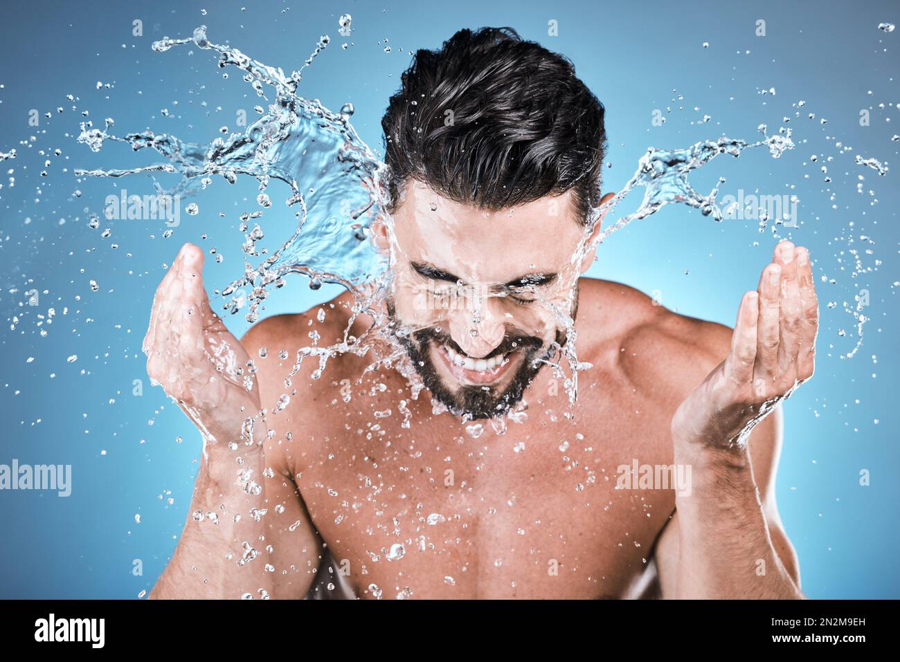 Water splash, hands and a man model washing his face in studio on a ...