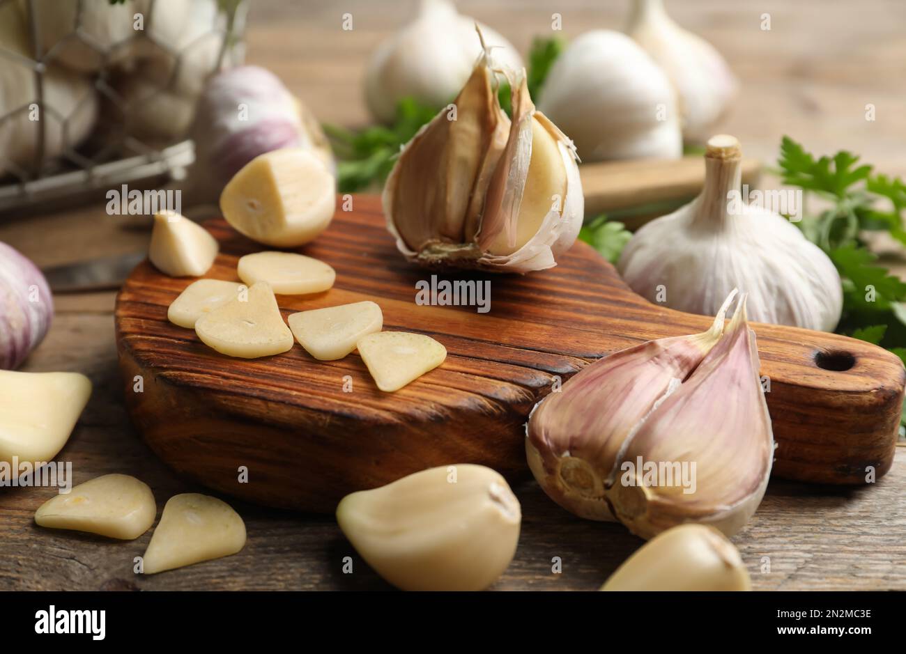 Fresh sliced and whole garlic on wooden table, closeup. Organic product ...