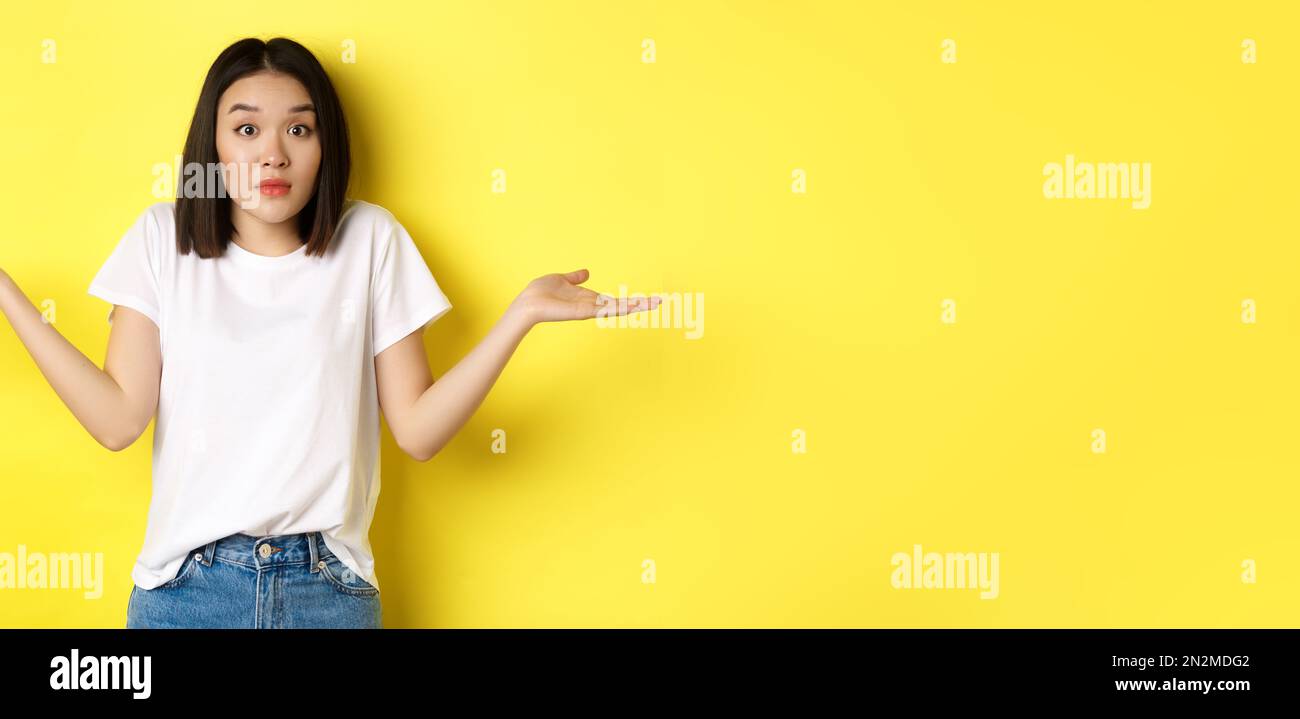 Clueless asian girl shrugging shoulders, spread out hands and looking ...