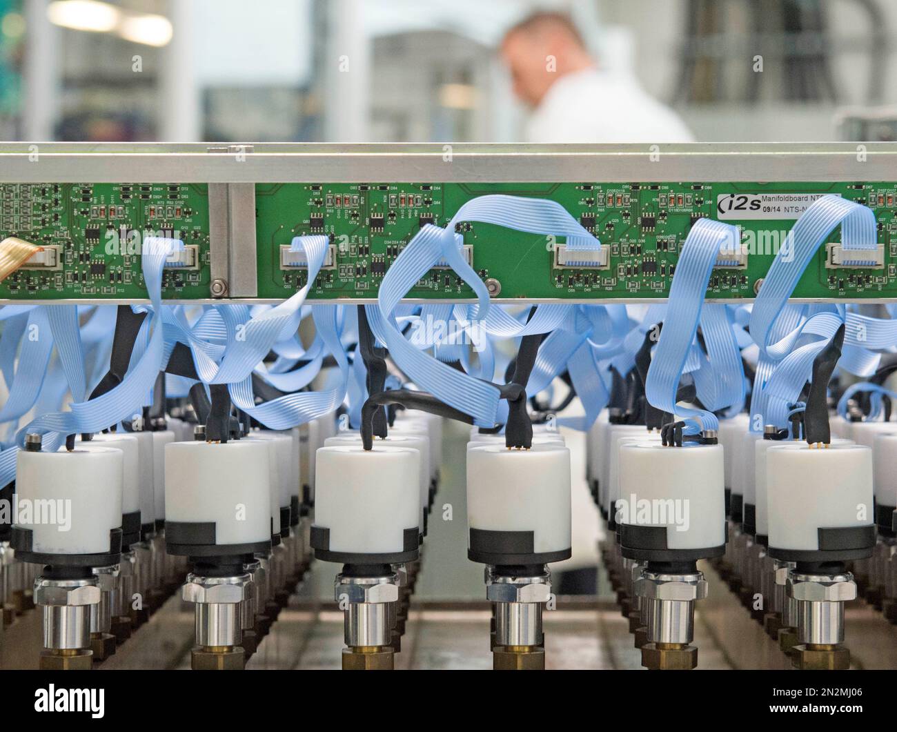 An employee works at an assembly line behind sensors during the ...