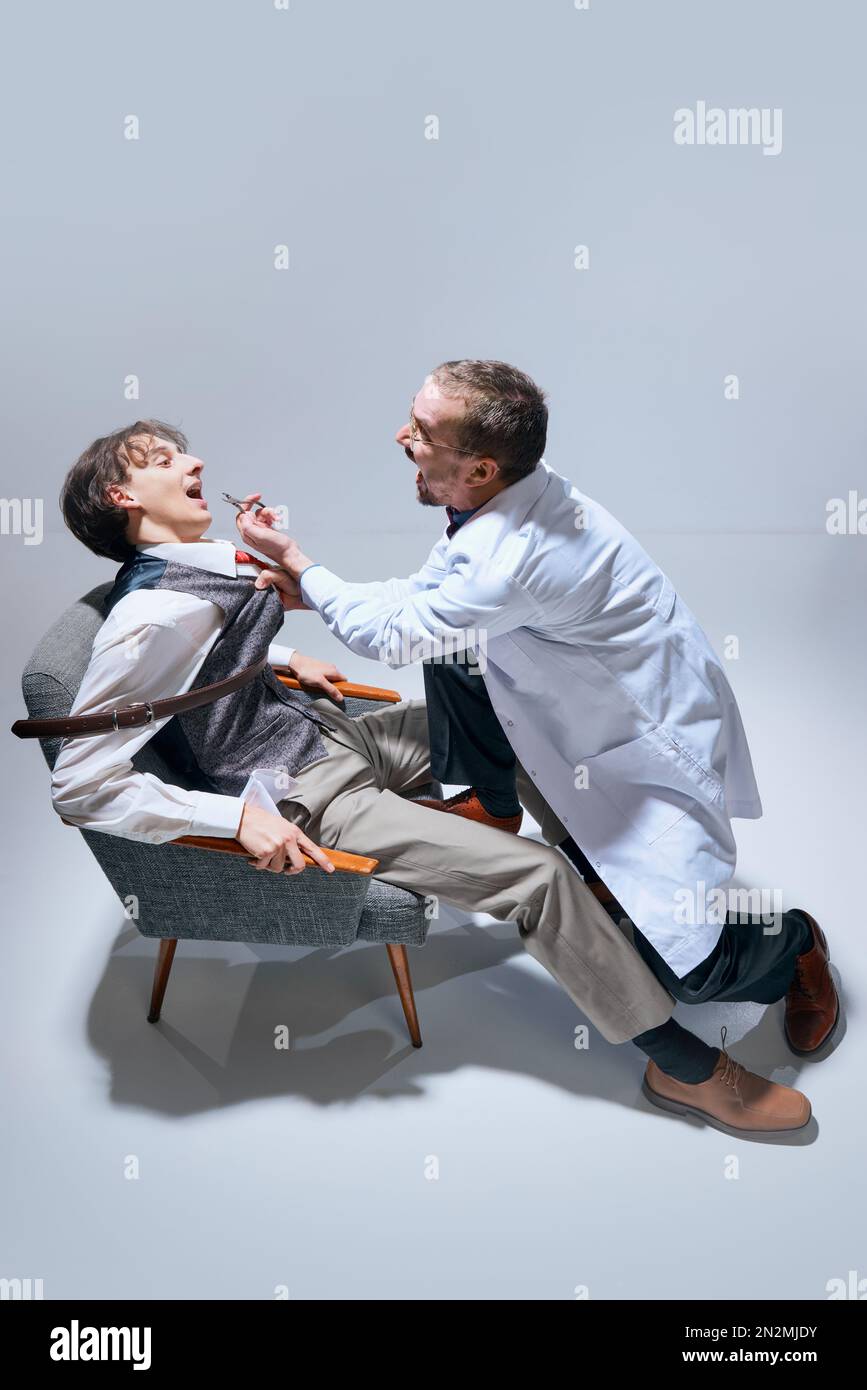 Young scared man sitting on chair, visiting dentist. Crazy insane ...