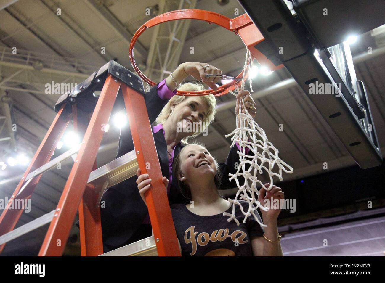 Iowa head coach Lisa Bluder. top, cuts down the net with help from her ...