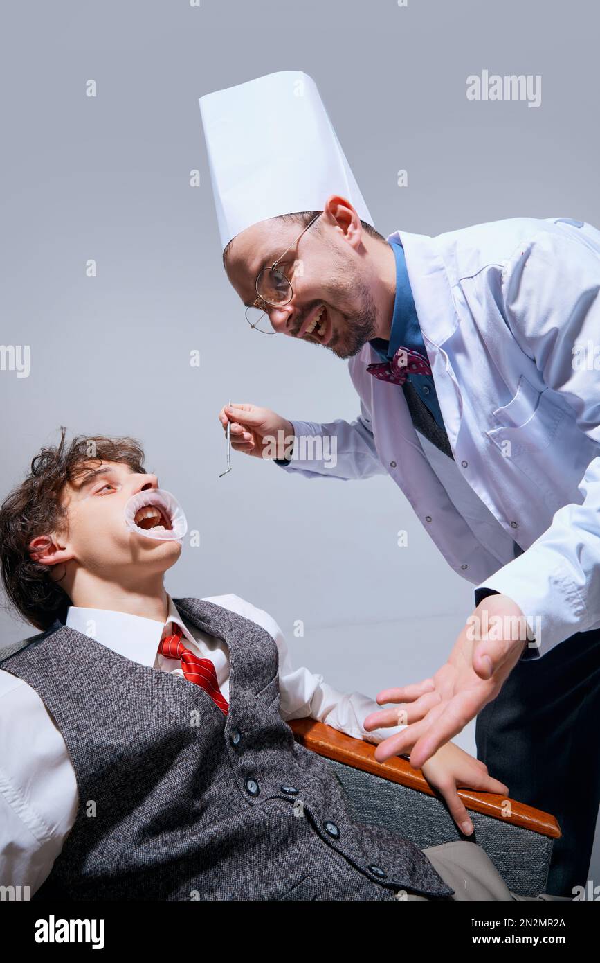 Young man visiting dentist. Doctor with crazy insane face checking male ...