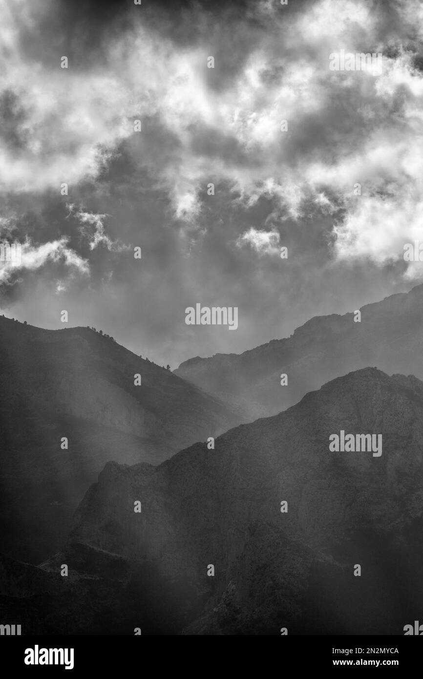 dramatic clouds over rugged mountains in black and white Stock Photo ...