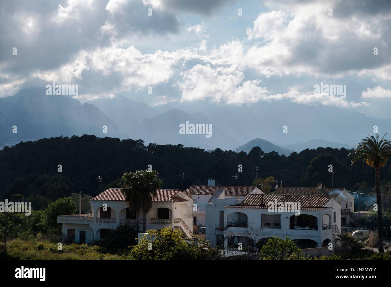 white walled mediterranean houses in lush green valley framed by rugged ...