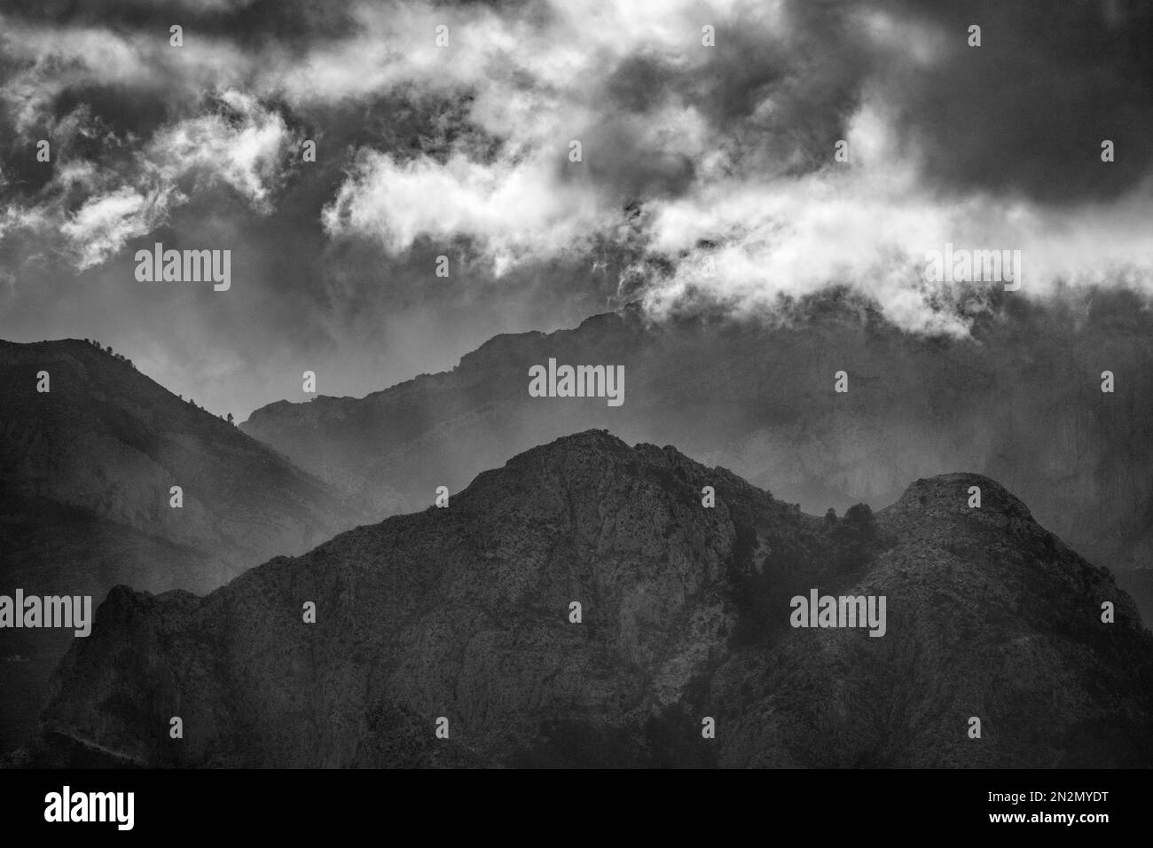 dramatic clouds over rugged mountains in black and white Stock Photo ...