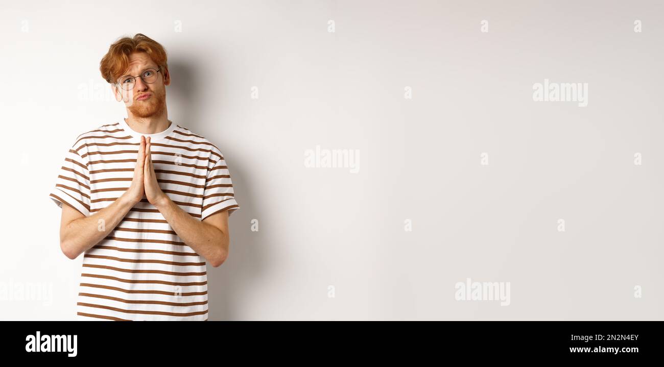 Silly redhead man asking for help, holding hands in pleading gesture ...