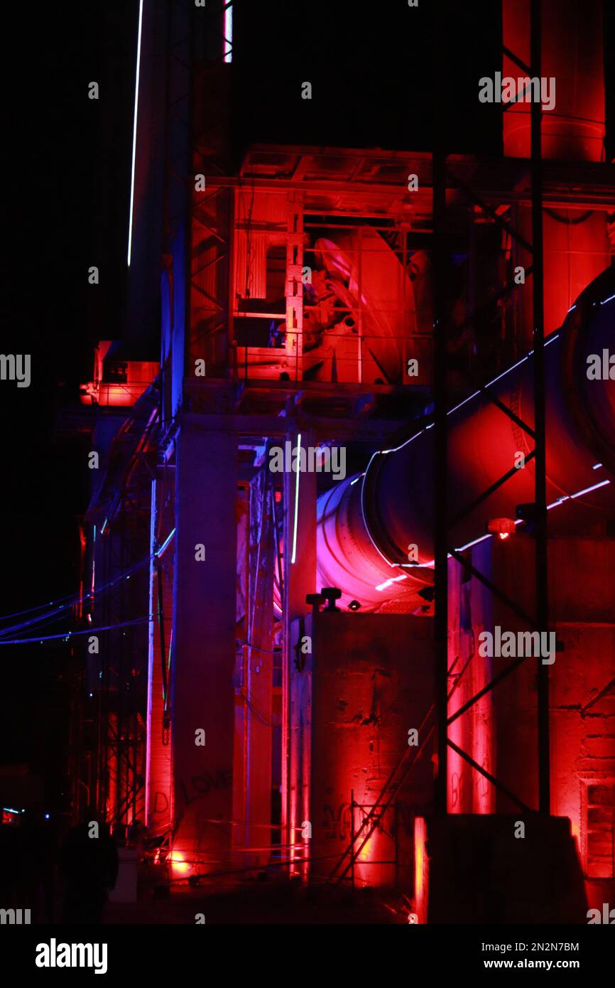 A vertical shot of an industrial building at night illuminated with ...
