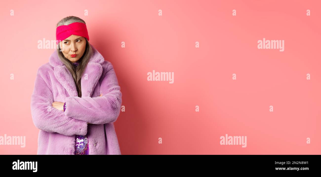 Grumpy funky old asian lady looking from under forehead, pouting and ...