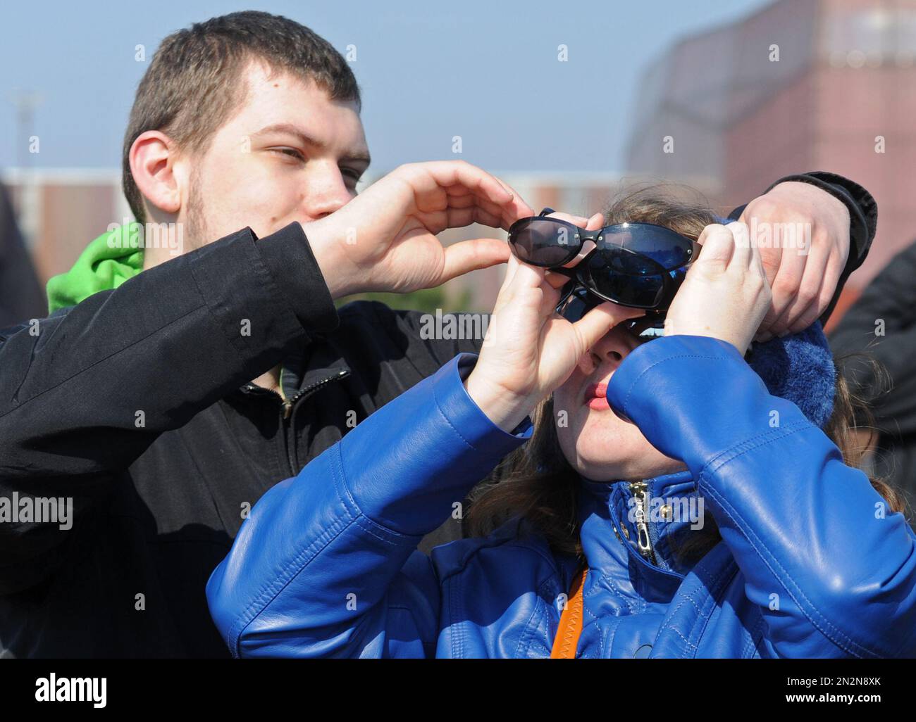 People watch a solar eclipse in Warsaw, Poland, Friday, March 20, 2015 ...