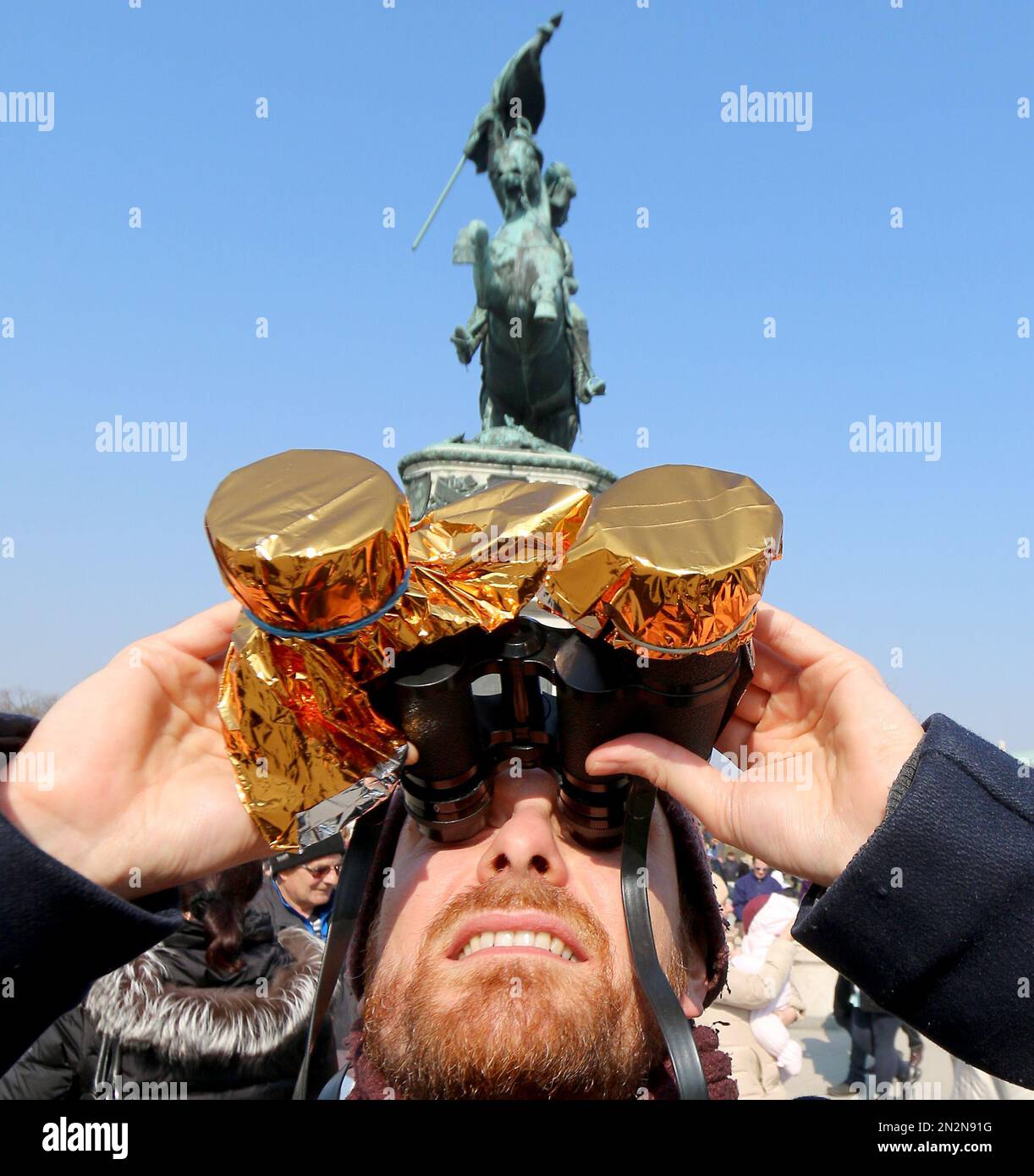 A man looks through special goggles during a solar eclipse in front of ...