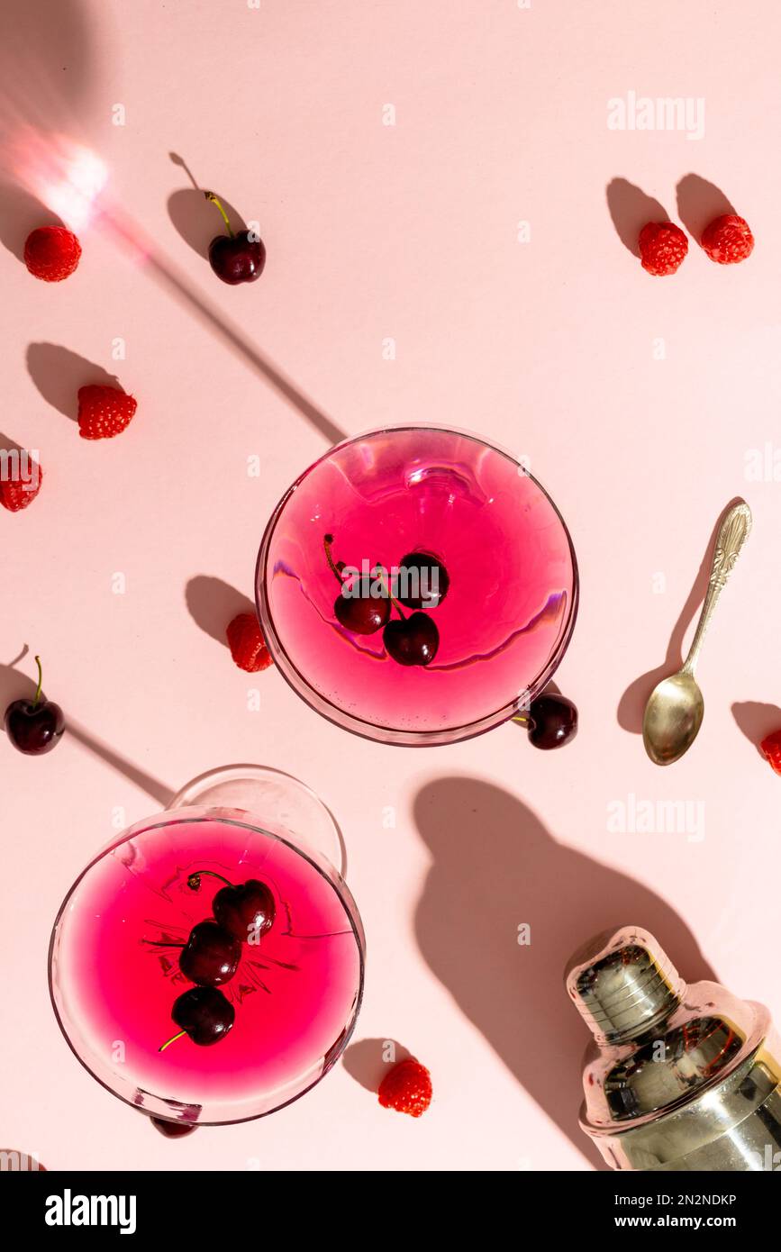 Vertical image of glasses with drinks and fruits over pale pink ...